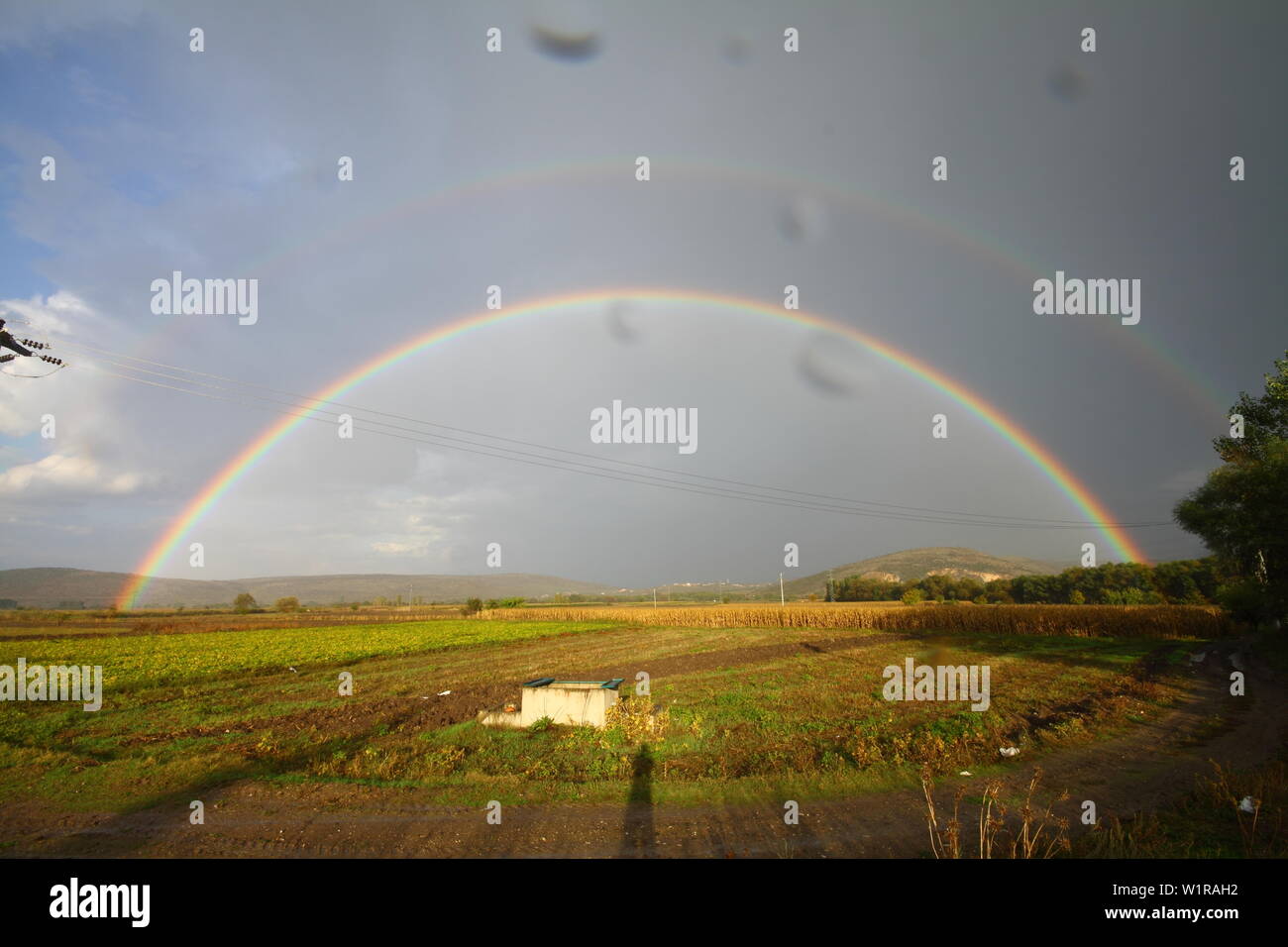 beautiful spring landscape panorama with a field and a rainbow above it ...