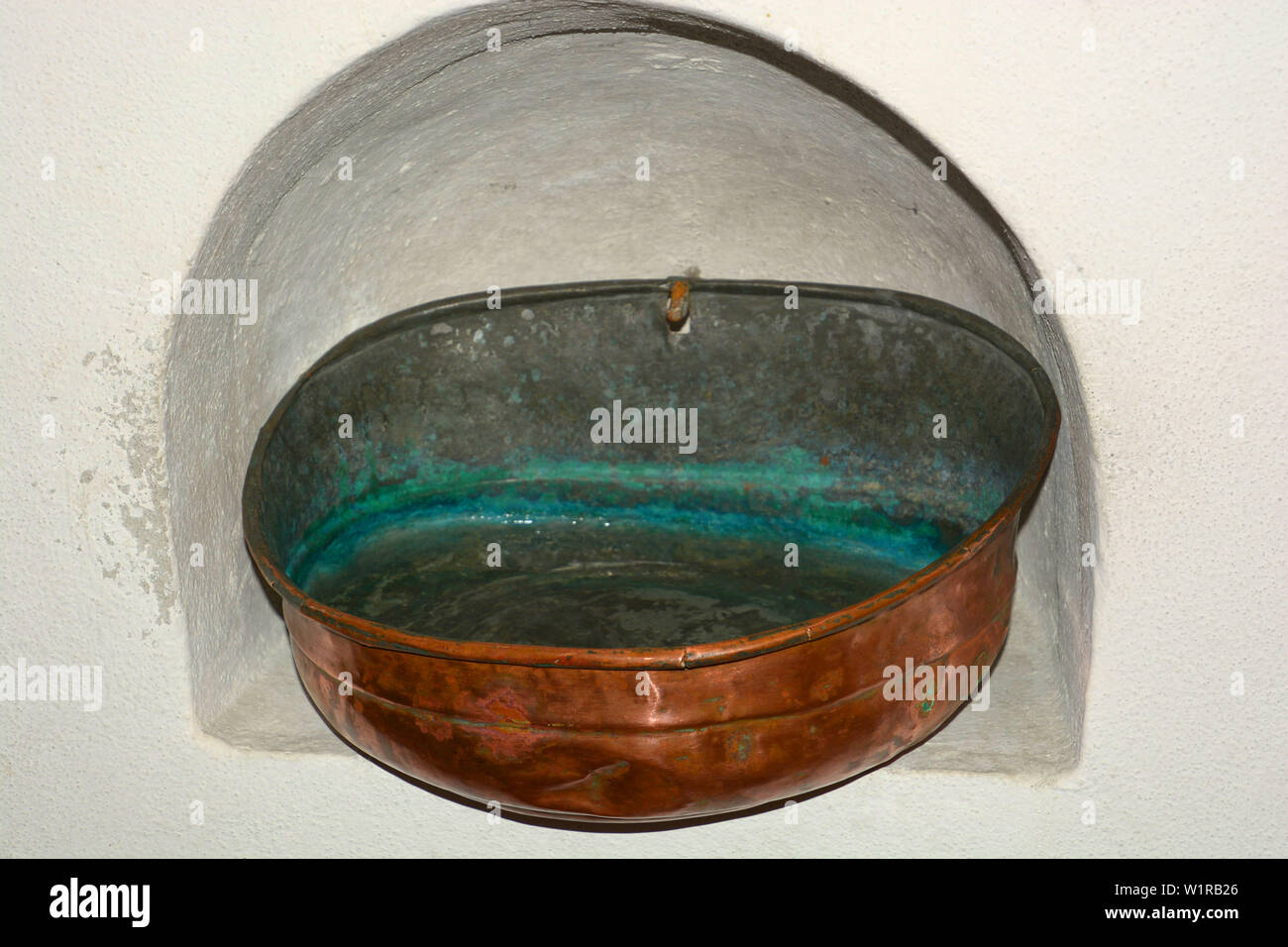 holy water in an old stoup made of copper with verdigris in the inside ...