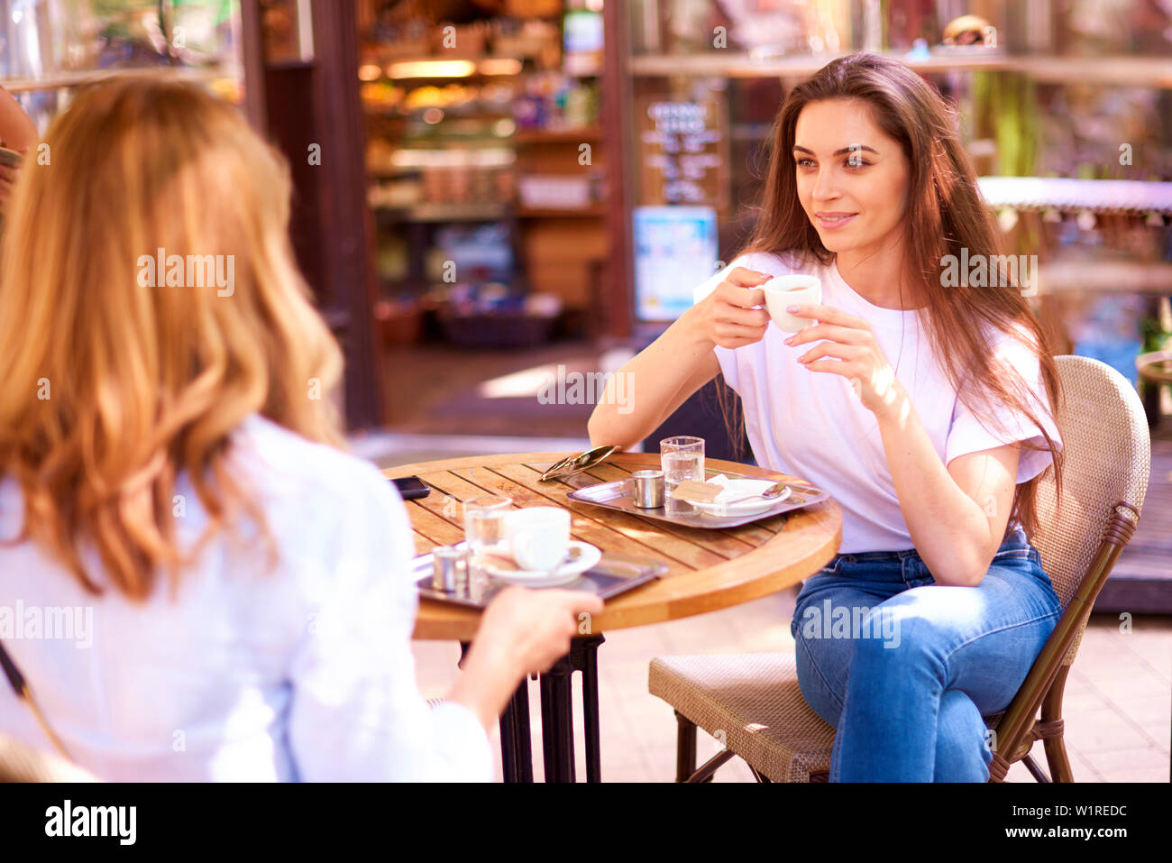 Shot of female friends talking in cafe while sitting at desk and having ...