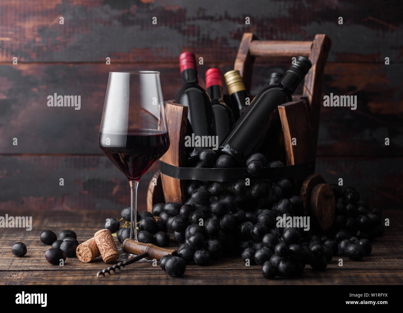 Elegant glass of red wine with dark grapes and mini bottles of wine ...