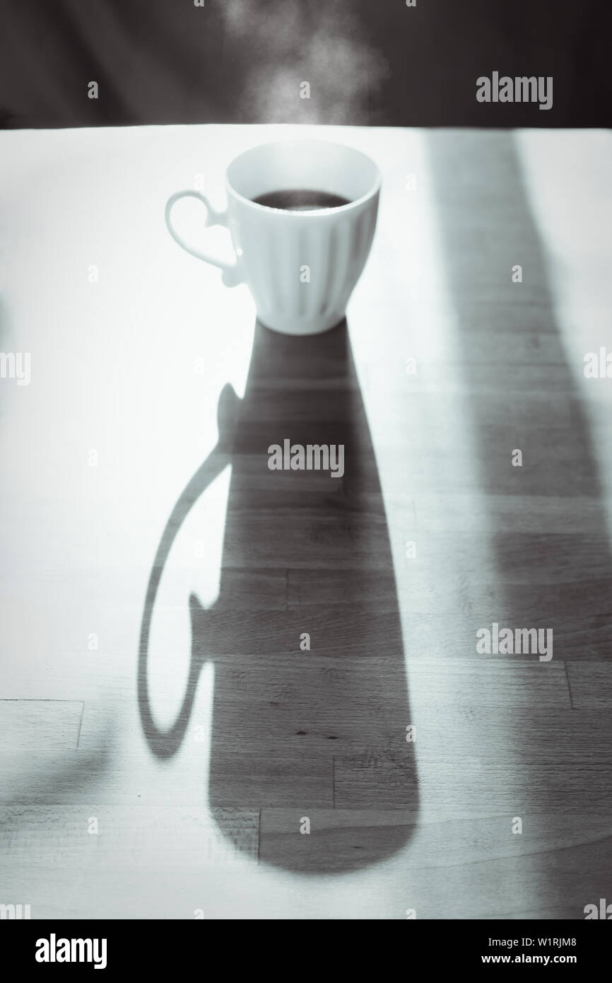 Coffee white cup standing on wooden table with long shadow side view ...