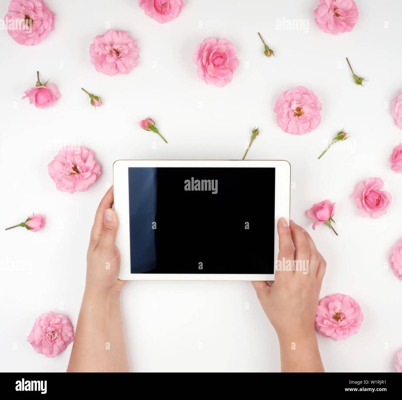 white electronic tablet with a blank black screen and two female hands ...