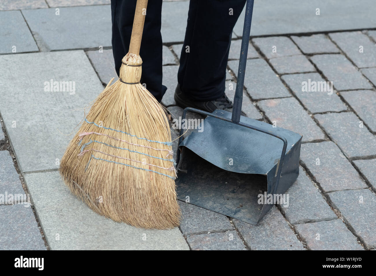 description: municipal worker sweep the road with broomstick and ...