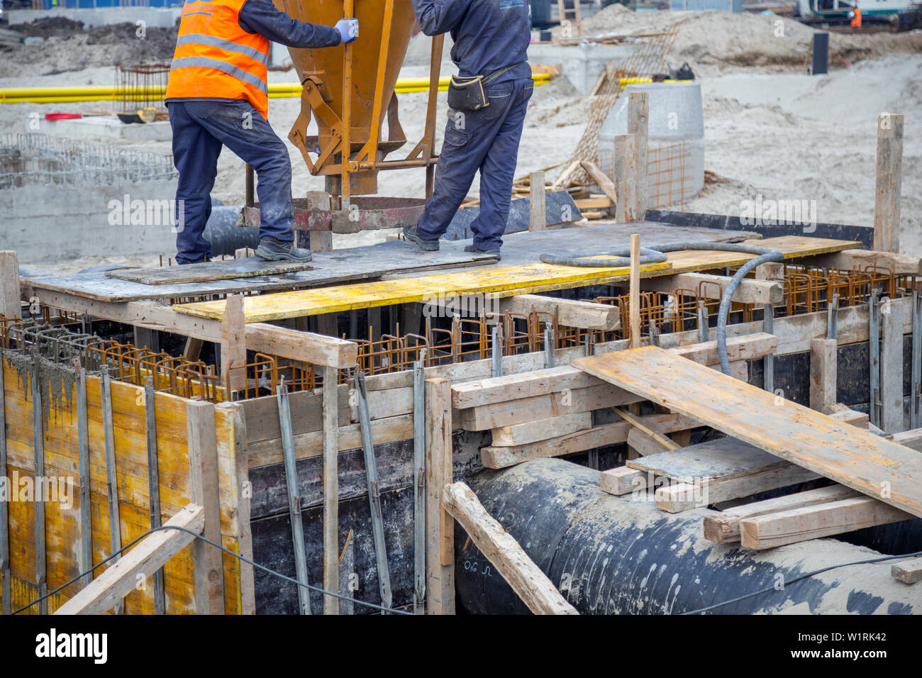 Construction workers pouring with concrete funnel skip for aiming and ...