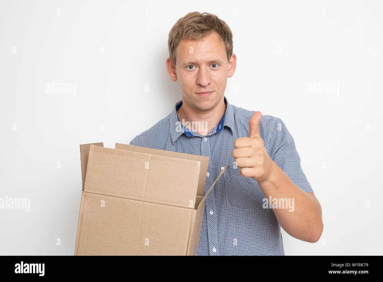 Description: curious man looking inside a cardboard box he holds in his ...