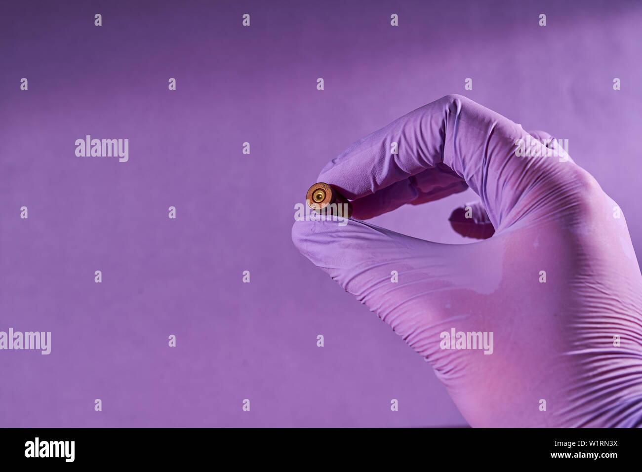 The hand of a man in a glove holding a bullet shell Stock Photo - Alamy