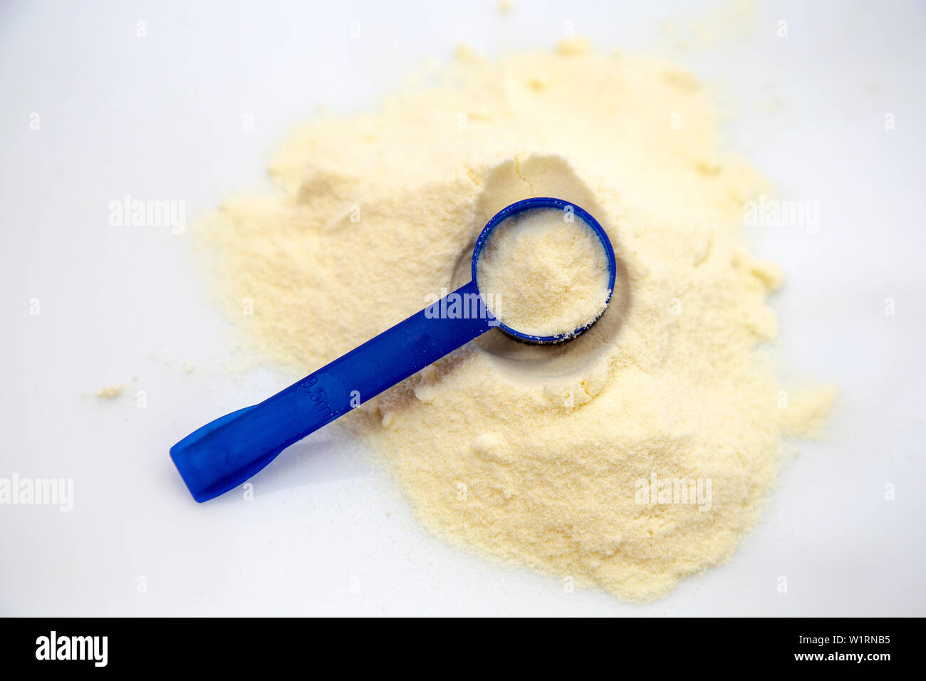 Powder milk food with blue spoon on white background Stock Photo - Alamy