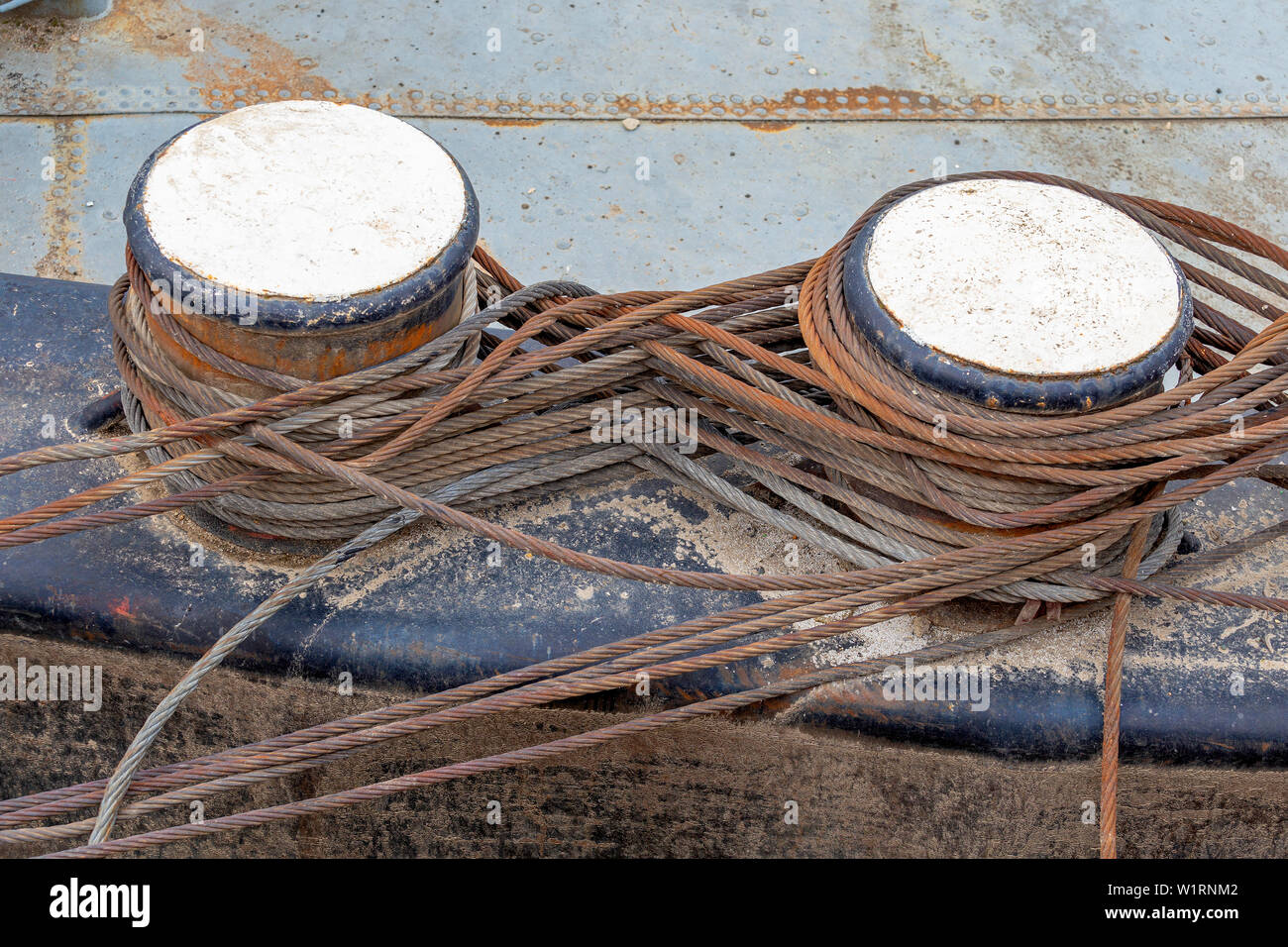 Steel wire rope and white mooring bollard in port, closeup and detail ...