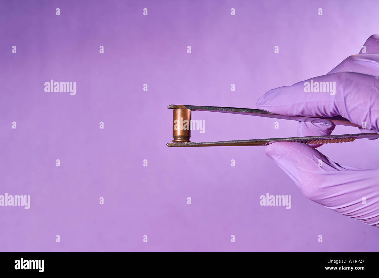 Man's gloved hand with tweezers and bullet casing Stock Photo - Alamy