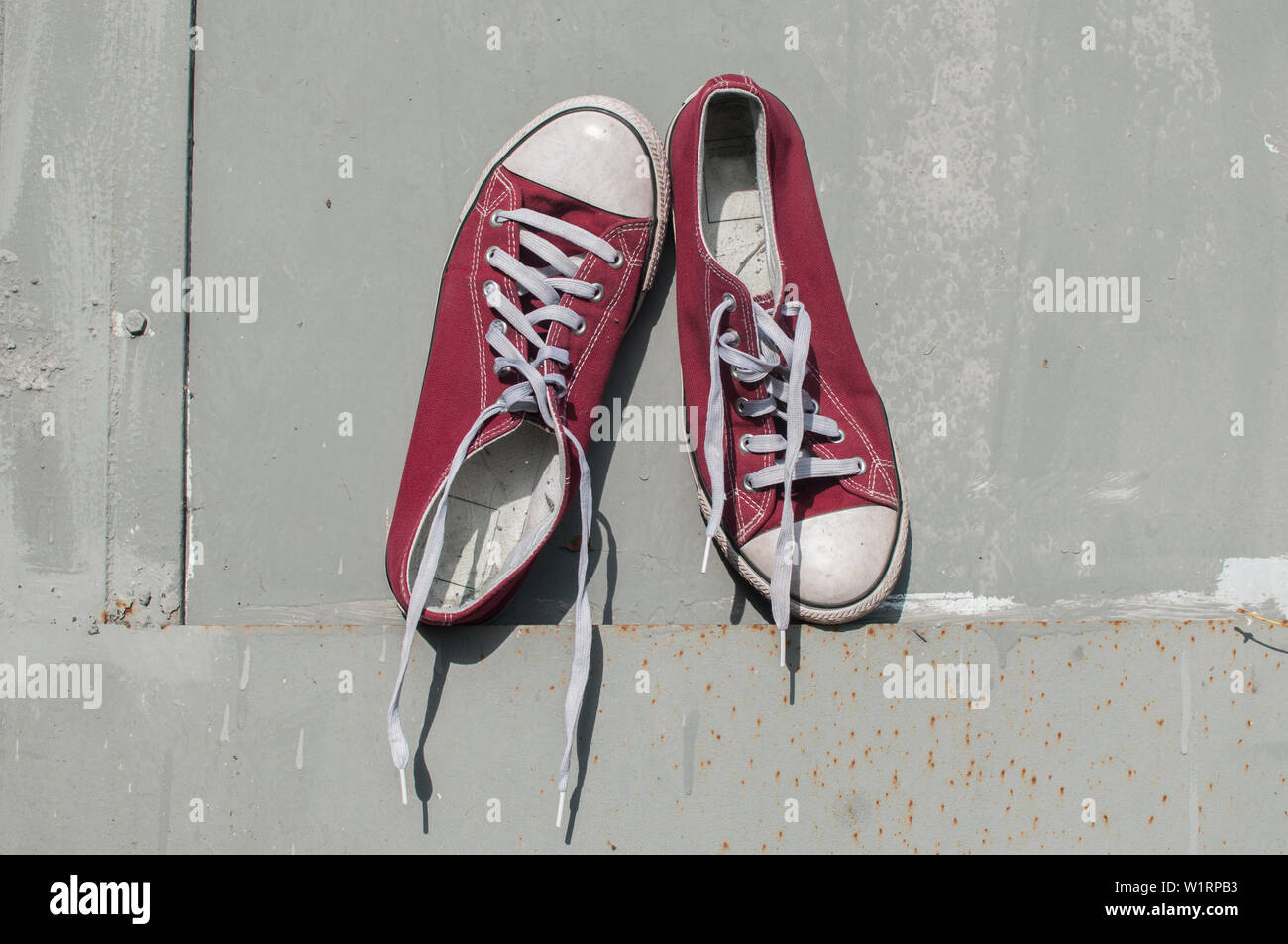 Pair of worn out vintage red old canvas sneakers on grey painted tin ...