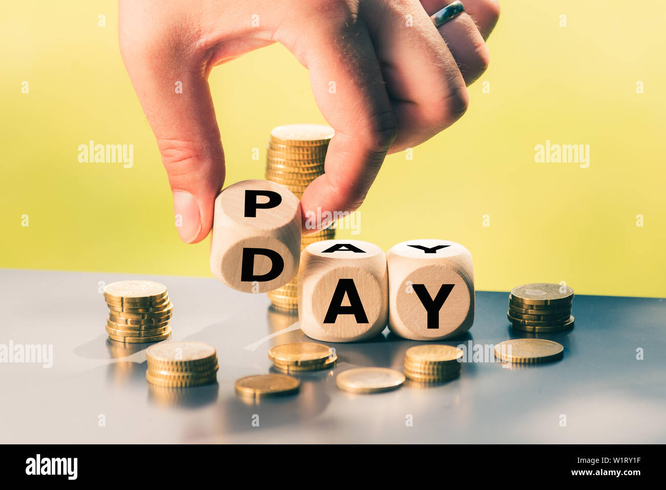 Hand is turning a dice and changes the word Pay to Day Stock Photo - Alamy
