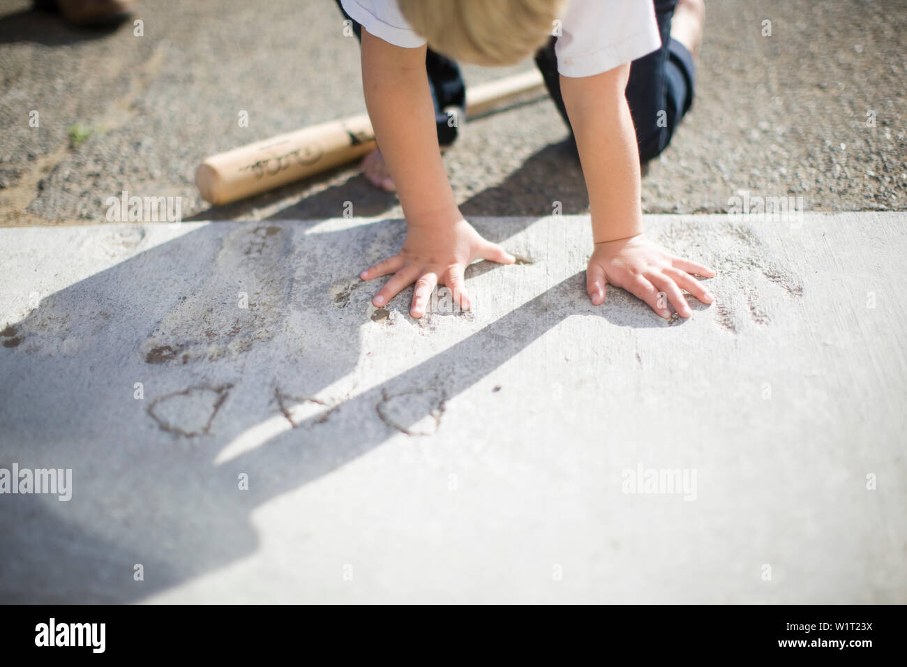 Little boy putting his hand in handprints made in concrete Stock Photo ...