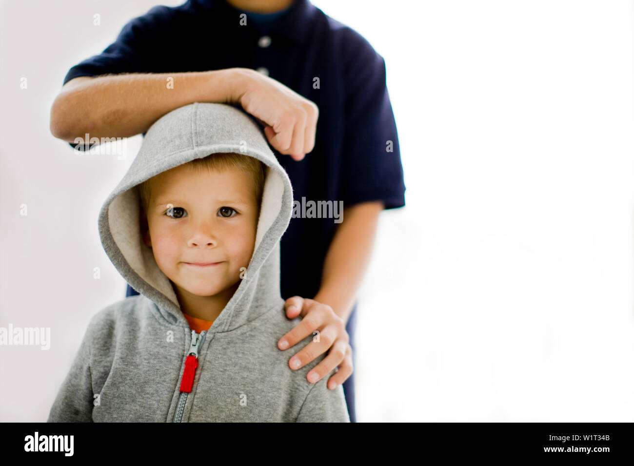 Portrait of a young boy standing in front of his older brother Stock ...