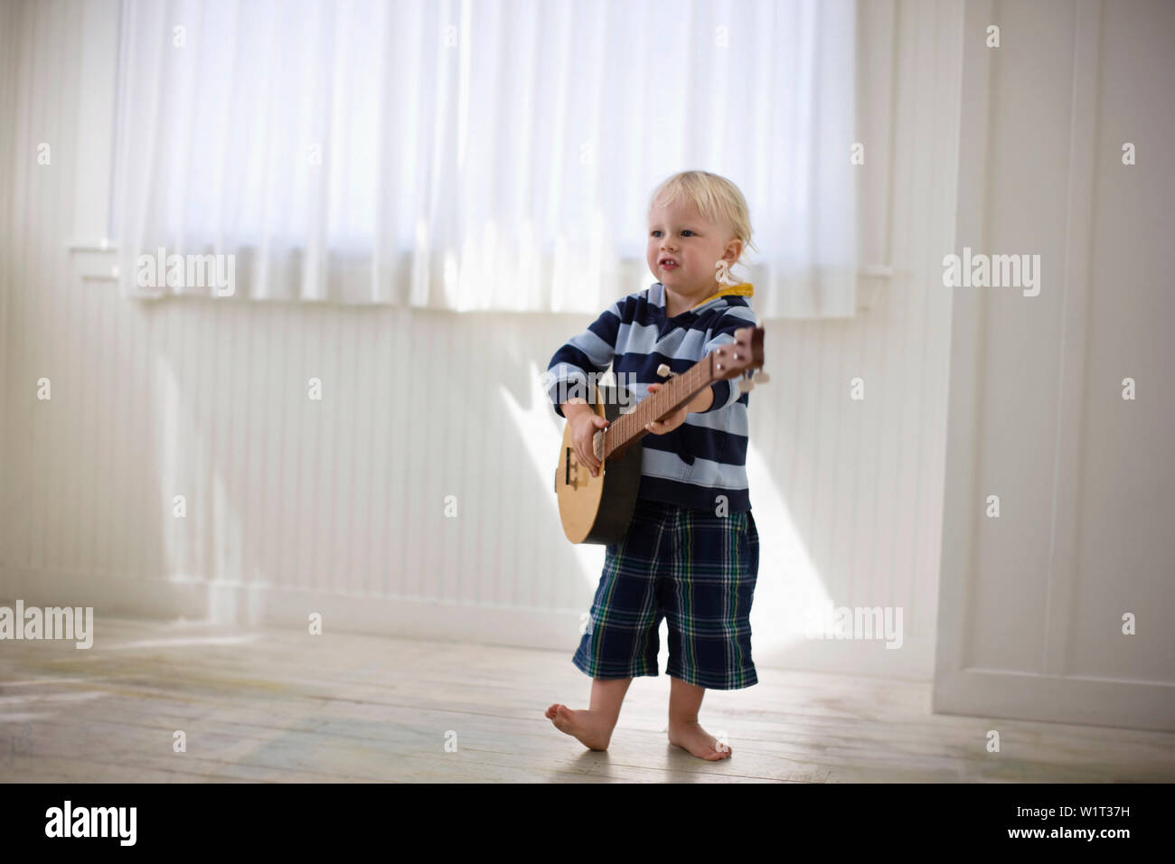 Toddler playing with a wooden banjo Stock Photo - Alamy
