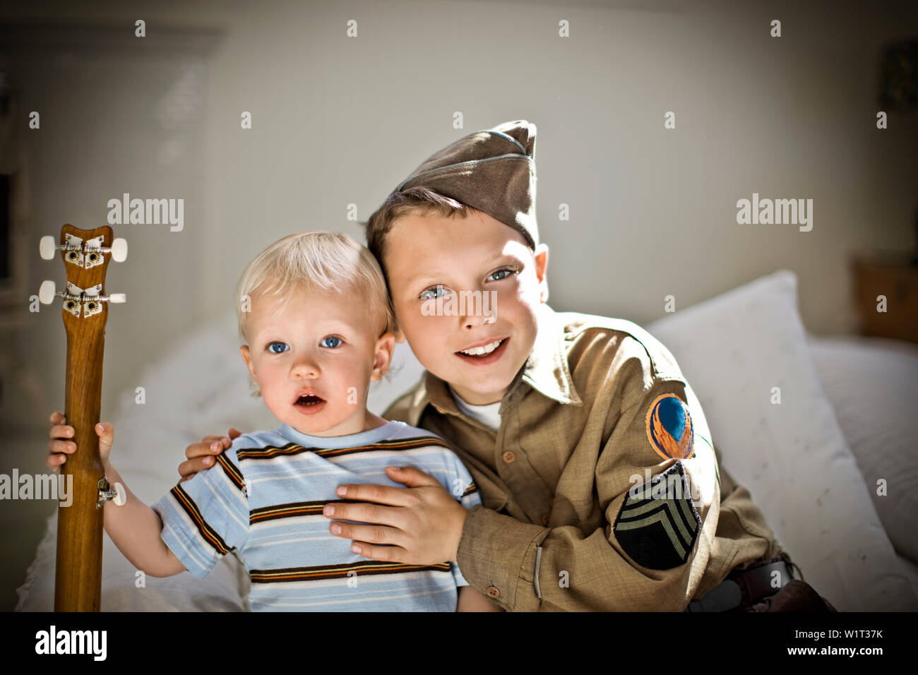 Portrait of a smiling boy sitting with his arm around his brother while ...