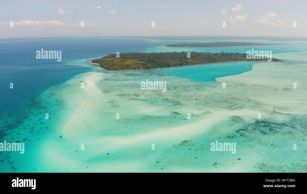 Travel concept: sandy beach on a tropical island by coral reef atoll ...