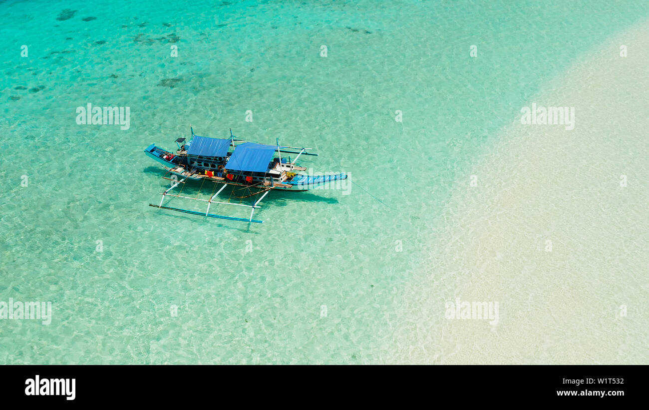 Boat on a tropical beach in the turquoise water of the lagoon from ...