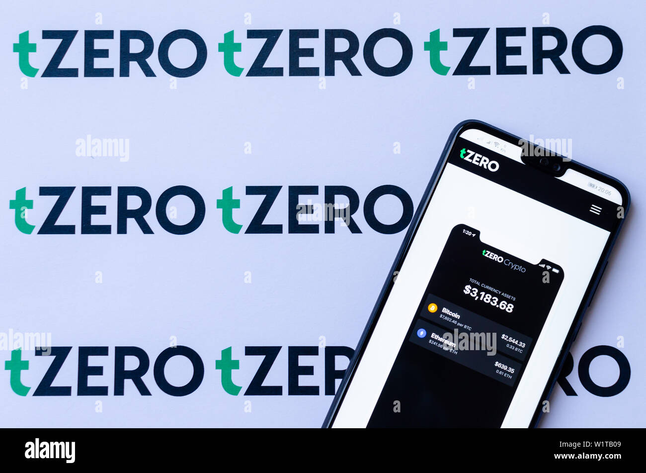 tZero logos on the brochure and the smartphone with the tZERO Crypto ...