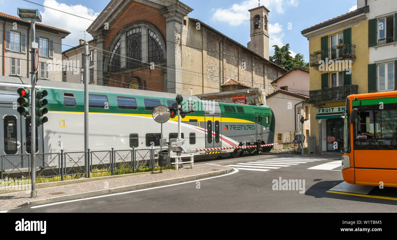 COMO, ITALY - JUNE 2019: Modern electric train passing over a road ...