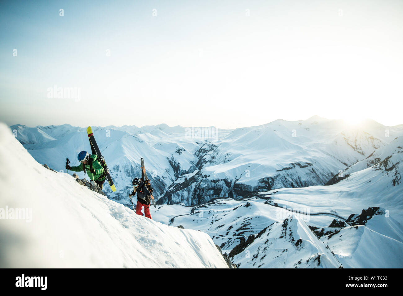Two young skiers hikiing up through the deep powder snow to a mountain ...