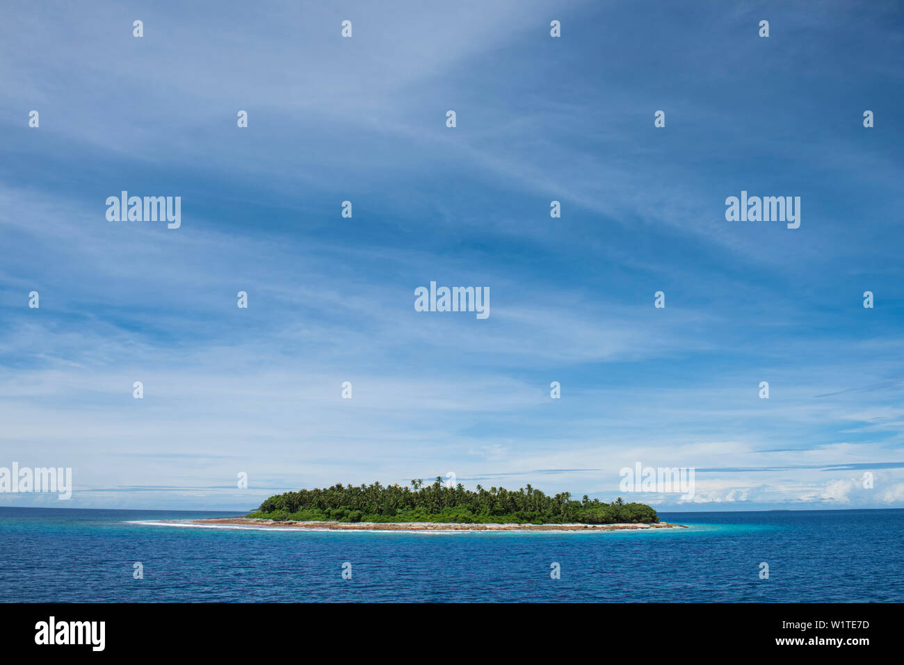 View of a small palm-covered island surrounded by turquoise and darker ...