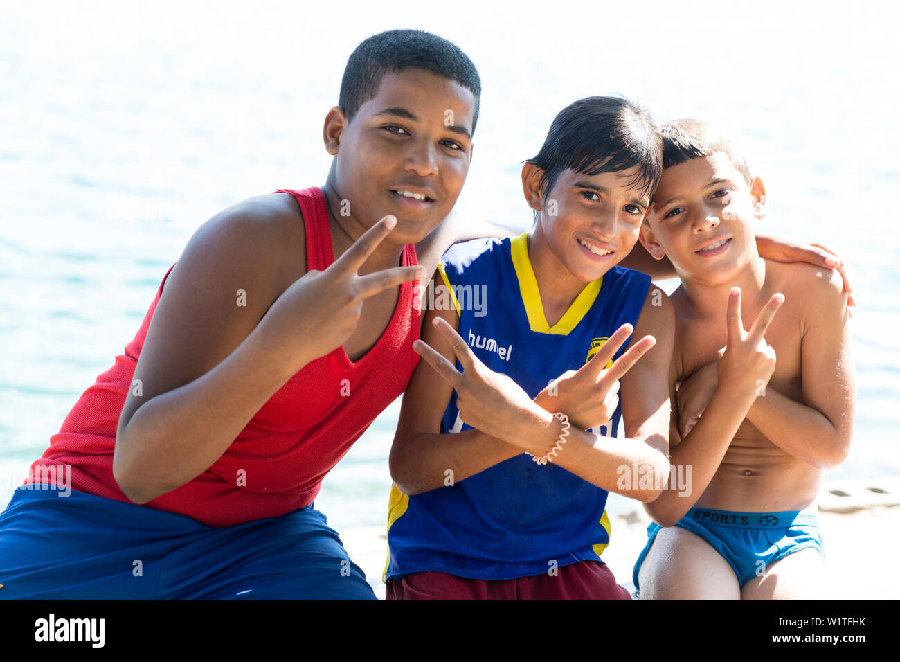 Three young local boys along the shore, victory sign, Cienfuegos, Cuba ...