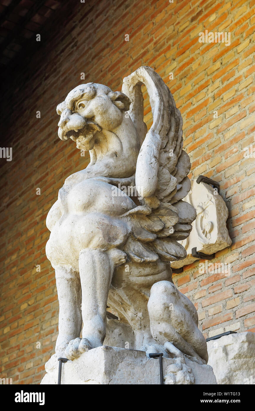 side view of a gargoyle carved in stone with a wall of bricks as ...