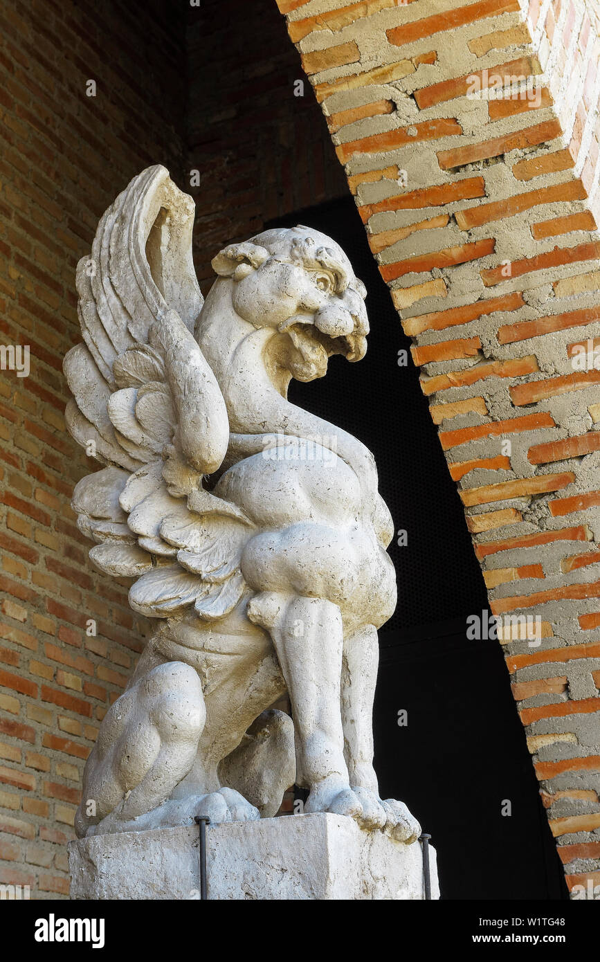side view of a gargoyle carved in stone with a wall of bricks as ...