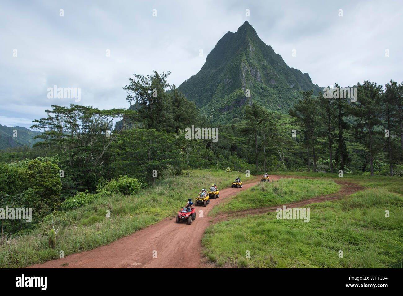 An excursion group of tourists on 4WD quad bikes on a rust red dirt ...