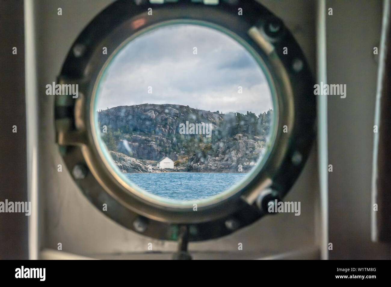 A view through a ships round porthole window on to a landscape scene ...