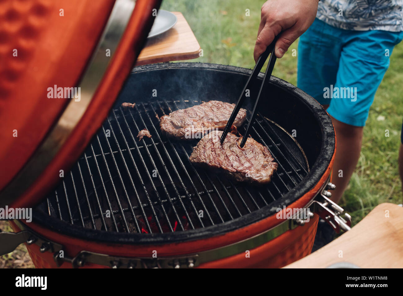 Close-up male hand grilled juicy piece of meat at barbecue high angle ...