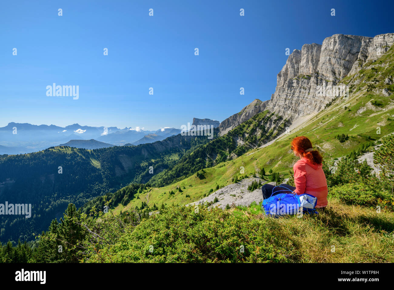 Woman while hiking sits on, paragraph and overlooks the mountain ...
