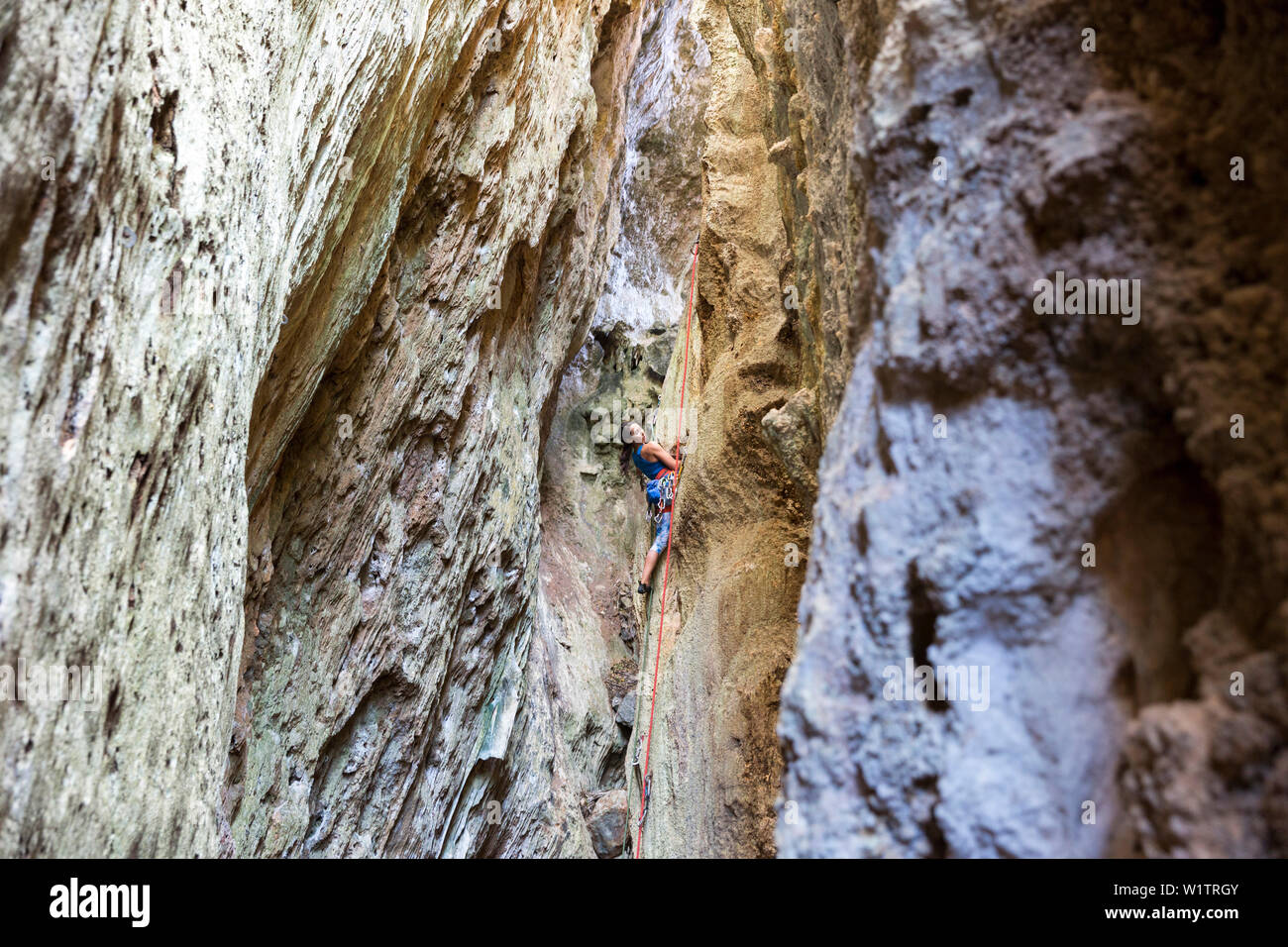 Female climber climbing in a cave, rock face, limestone, rock climbing ...