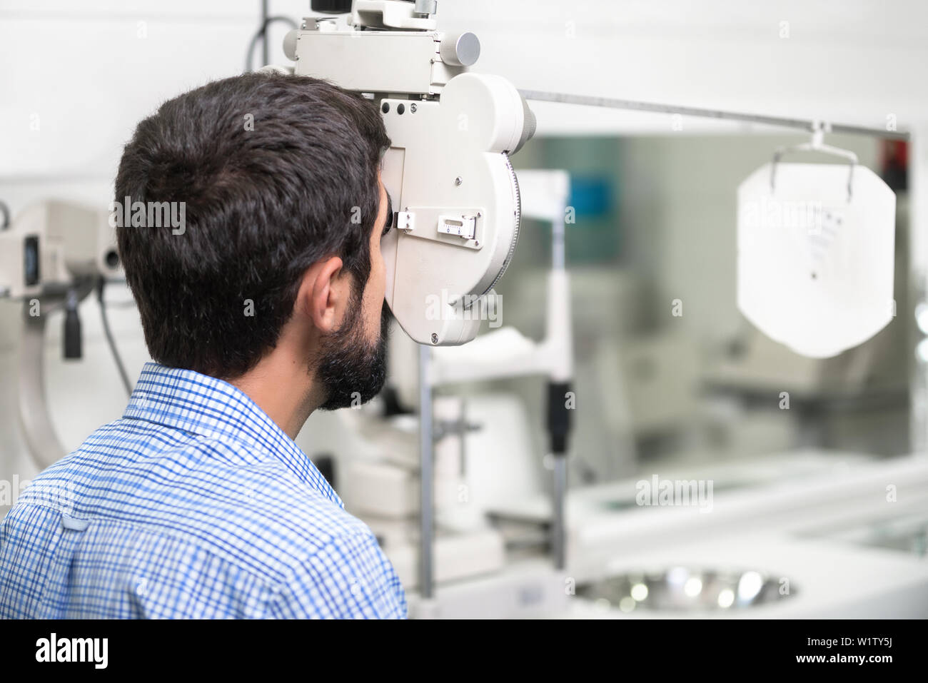 Patient is reading the optometrist chart in modern ophthalmology clinic ...