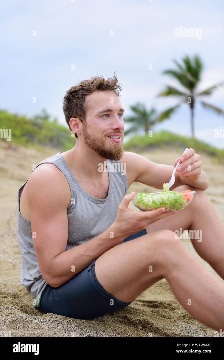 Fitness man eating healthy salad meal at workout. Handsome young ...