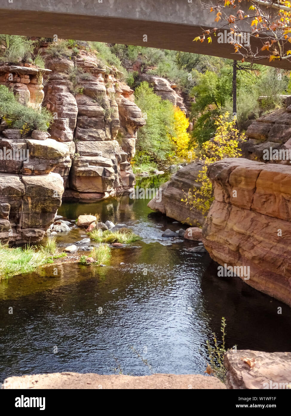River running under a bridge with Red Rocks in Slide Rock State Park ...