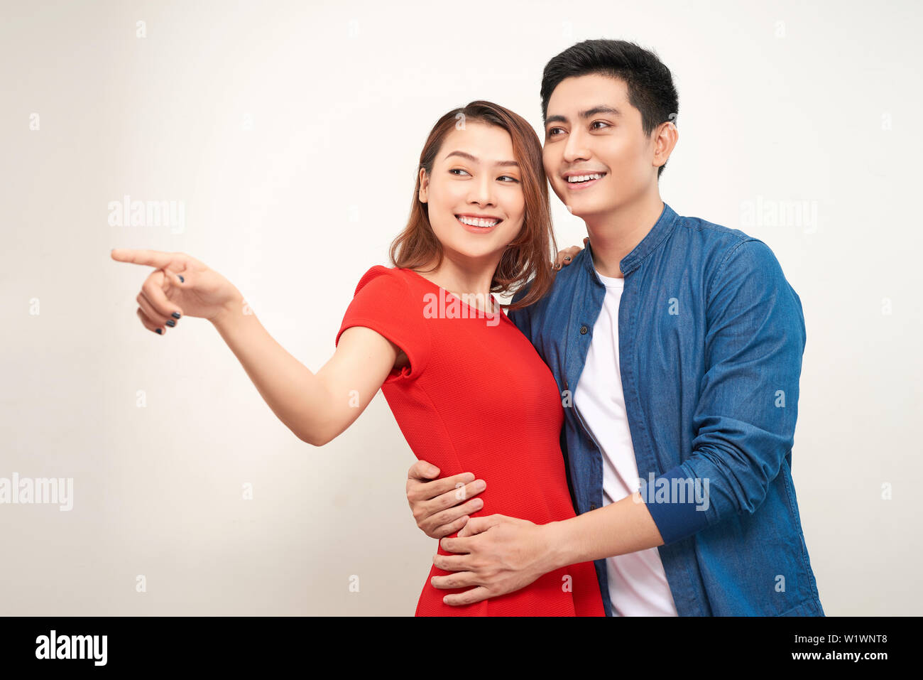 Woman points at something. Both lovers looking at camera. Isolated on ...