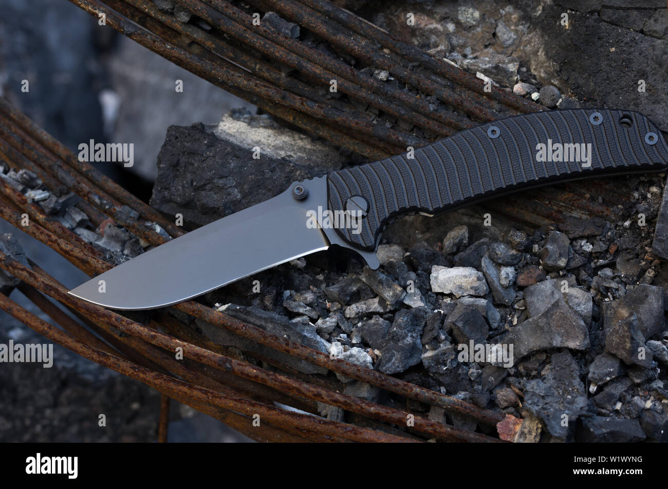 Folding knife. The knife is black. Dramatic composition. Front view ...