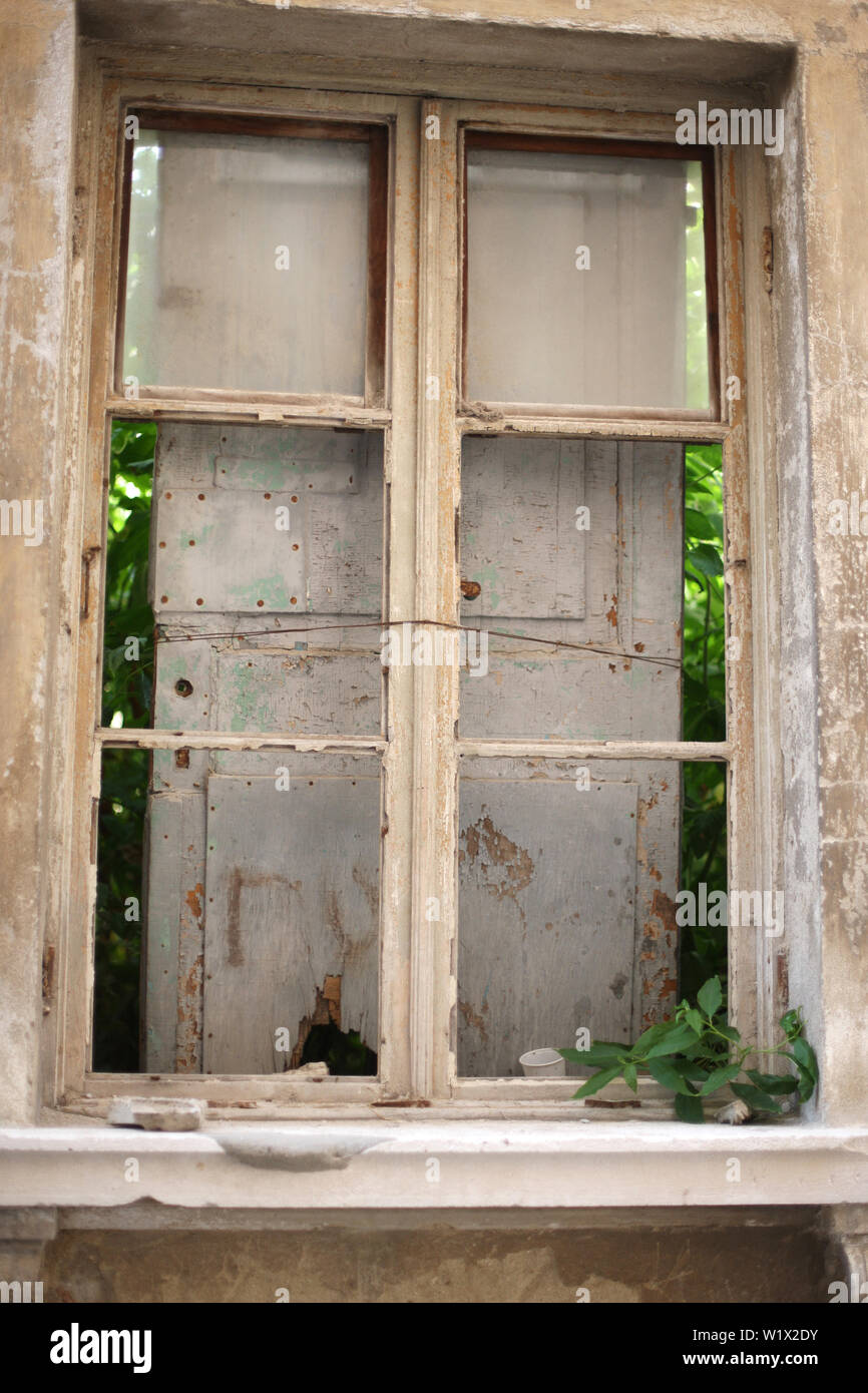The window of a dilapidated house is blocked with a door removed from ...