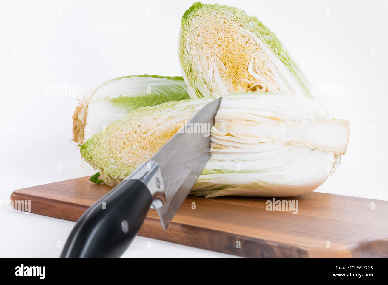 Two half of Chinese cabbage with knife on chopper board isolated on ...