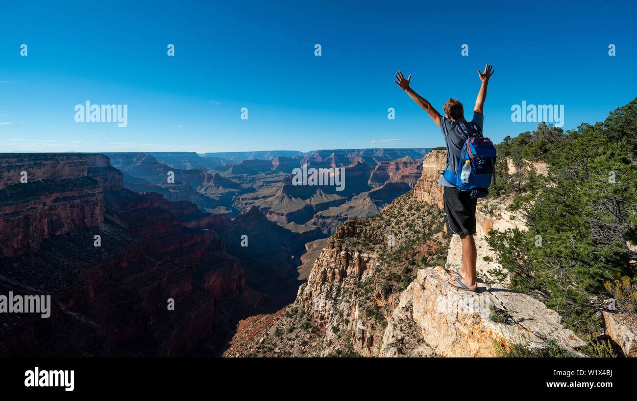 Young man stretches his arms into the air, canyon landscape, eroded ...