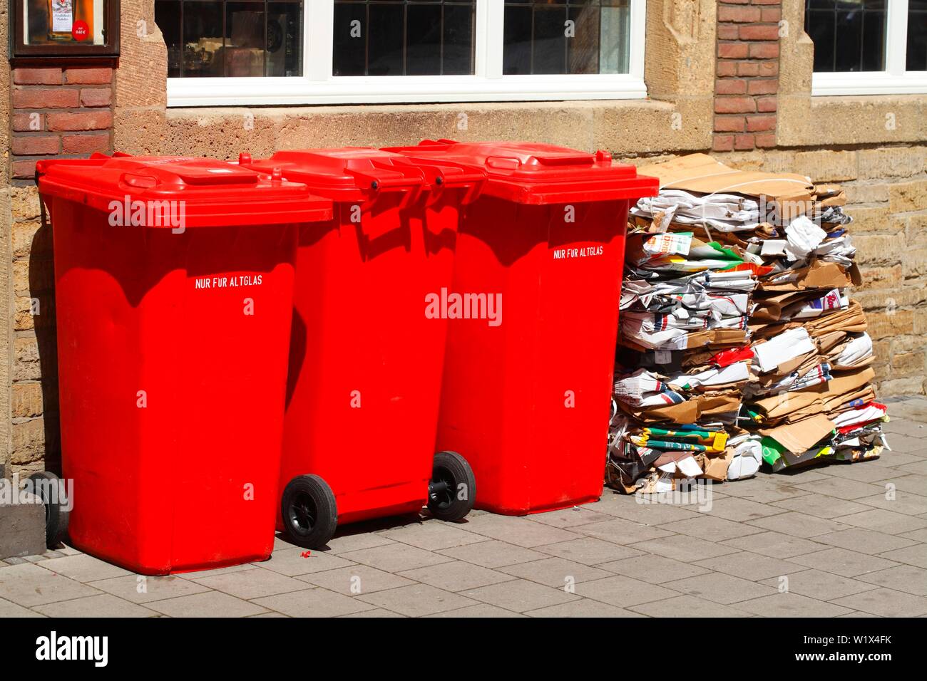 Red bins for waste glass and stacks of waste paper, Germany, Europe ...