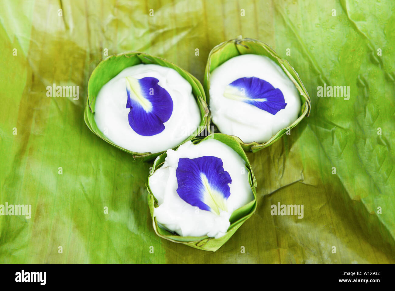 Thai pudding with coconut topping with Butterfly pea flowers on banana ...