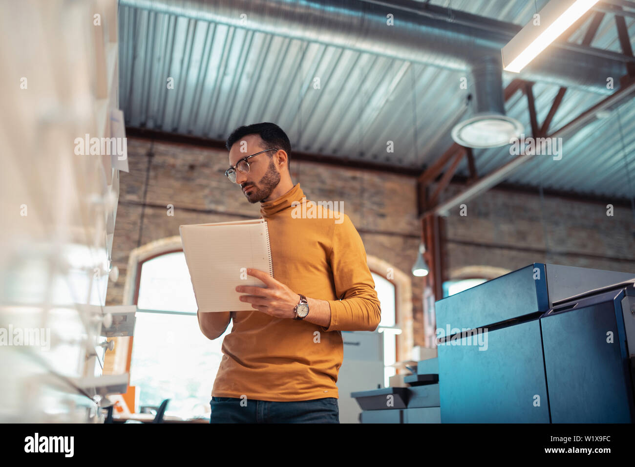 Man with notebook. Low angle of handsome bearded man wearing jeans ...