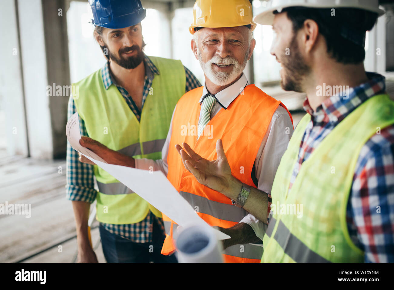 Engineer, foreman and worker discussing in building construction site ...