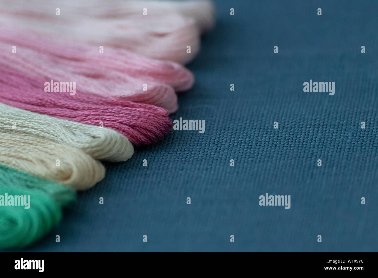 Multi-colored threads for embroidery on blue canvas. Place for text ...