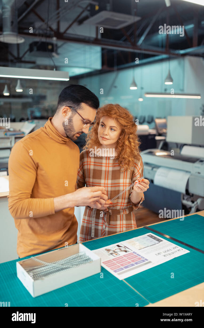 Looking at colleague. Red-haired beautiful graphic designer looking at ...