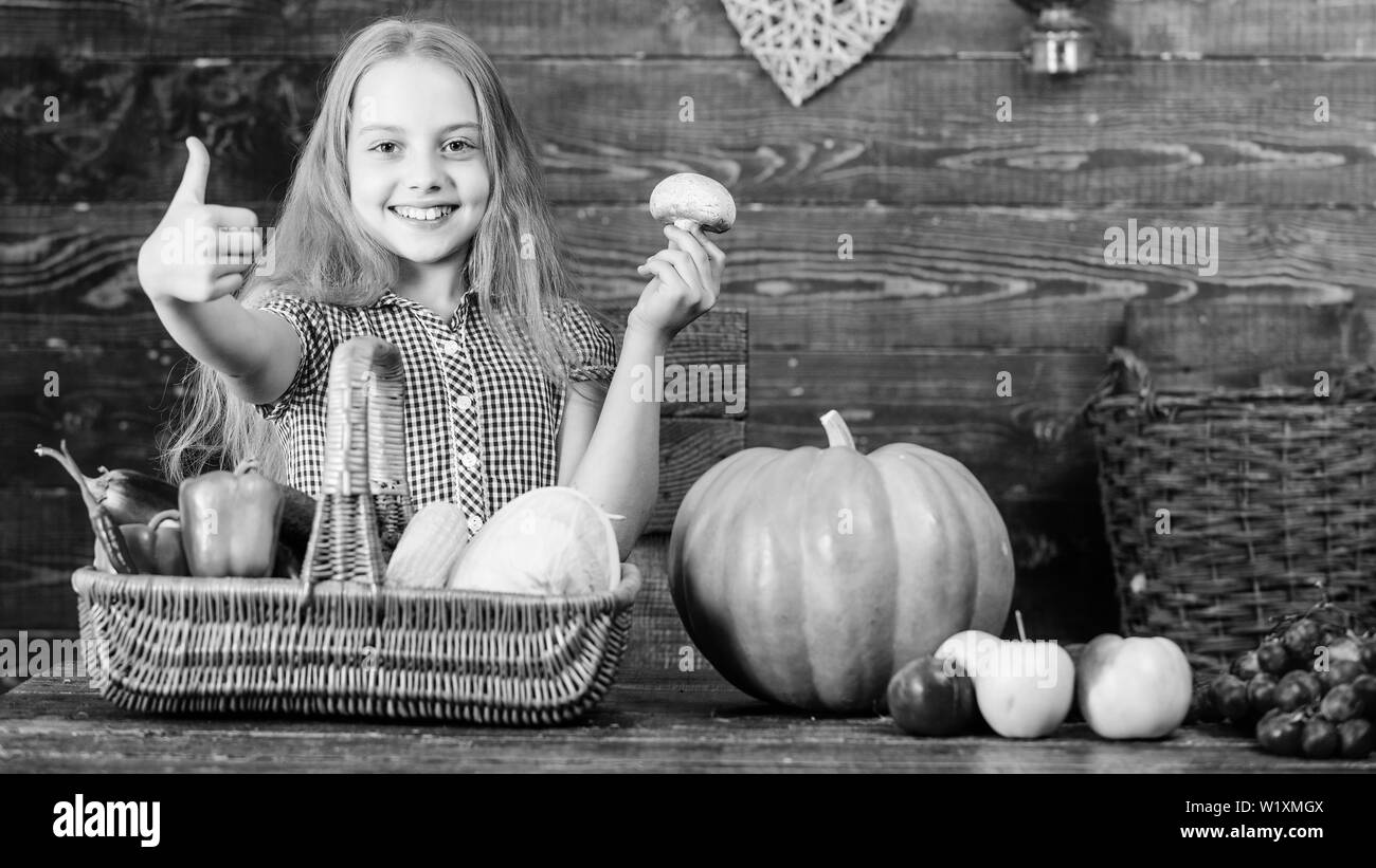 Child girl presenting harvest of her vegetable garden on wooden ...