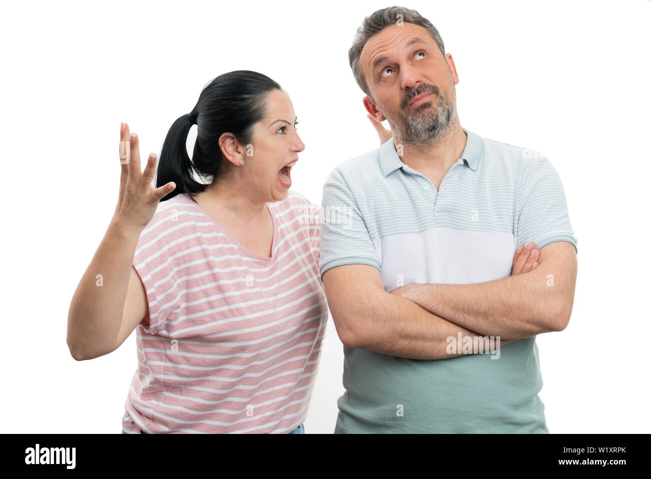Angry woman yelling at man with careless expression and crossed arms ...
