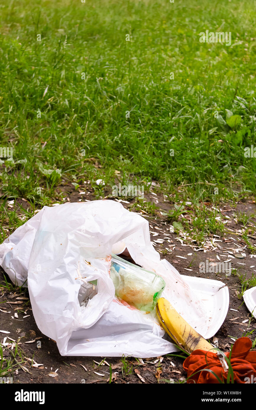 Crumpled plastic bag with trash and disposable utensils on the grass in ...